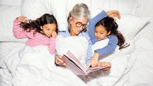 Cama com roupa de cama branca e um livro.