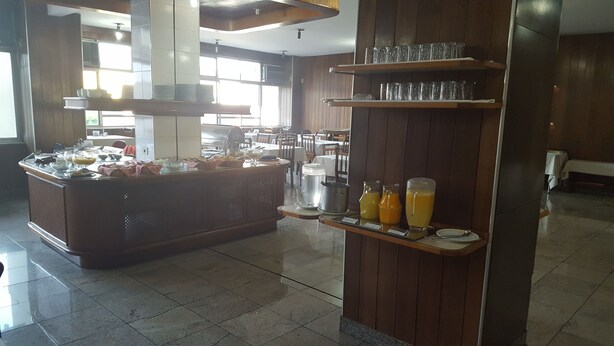 Uma área de buffet com diversas opções de comida e bebidas, incluindo uma variedade de frutas e um espaço para sucos.