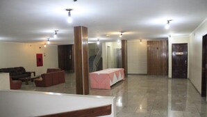 Um hall amplo com balcão de recepção, área de estar e escadaria para um andar superior.
