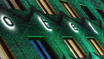 Fachada de edifício com padrão de tijolos e janelas iluminadas.