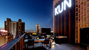 Um bar no terraço com vista para o horizonte urbano ao entardecer.