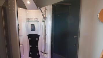 Uma casa de banho moderna com banheira de hidromassagem envidraçada, zona de duche separada e toucador com espelho.
