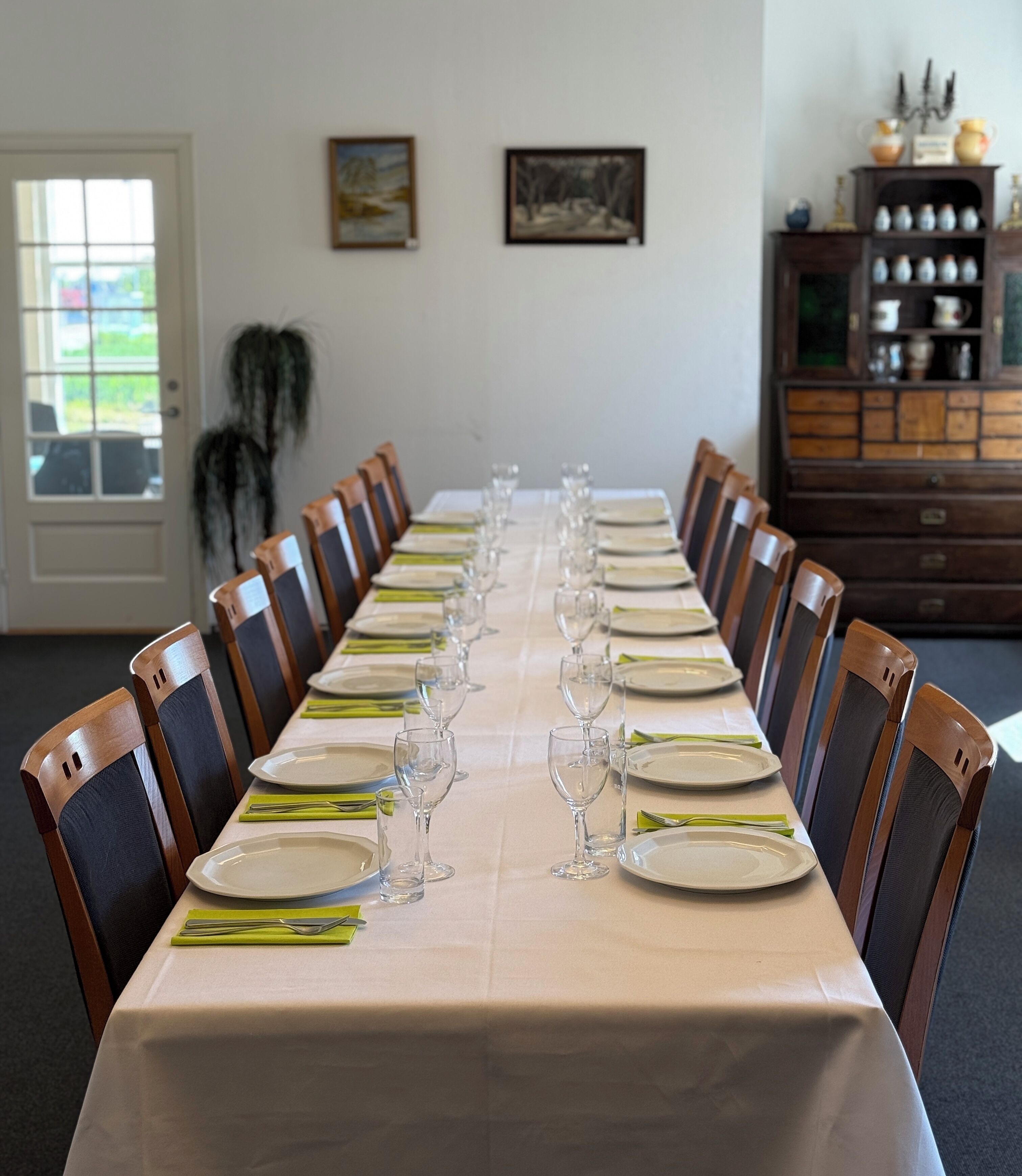 Mesa posta para refeição, com cadeiras, pratos e copos de vinho.