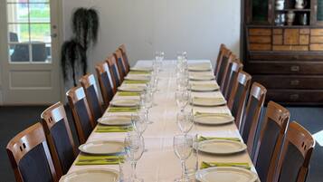 Mesa posta para refeição, com cadeiras, pratos e copos de vinho.