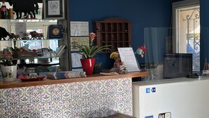 Uma área de recepção de hotel com parede revestida de azulejos, balcão de madeira e monitor de computador.