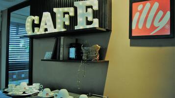 Café iluminado com as letras 'CAFE', um sinal da 'illy' e vista para a janela.