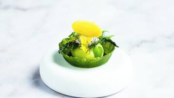 Um prato branco com uma tigela verde contendo um objeto amarelo, possivelmente comida, sobre uma superfície branca.