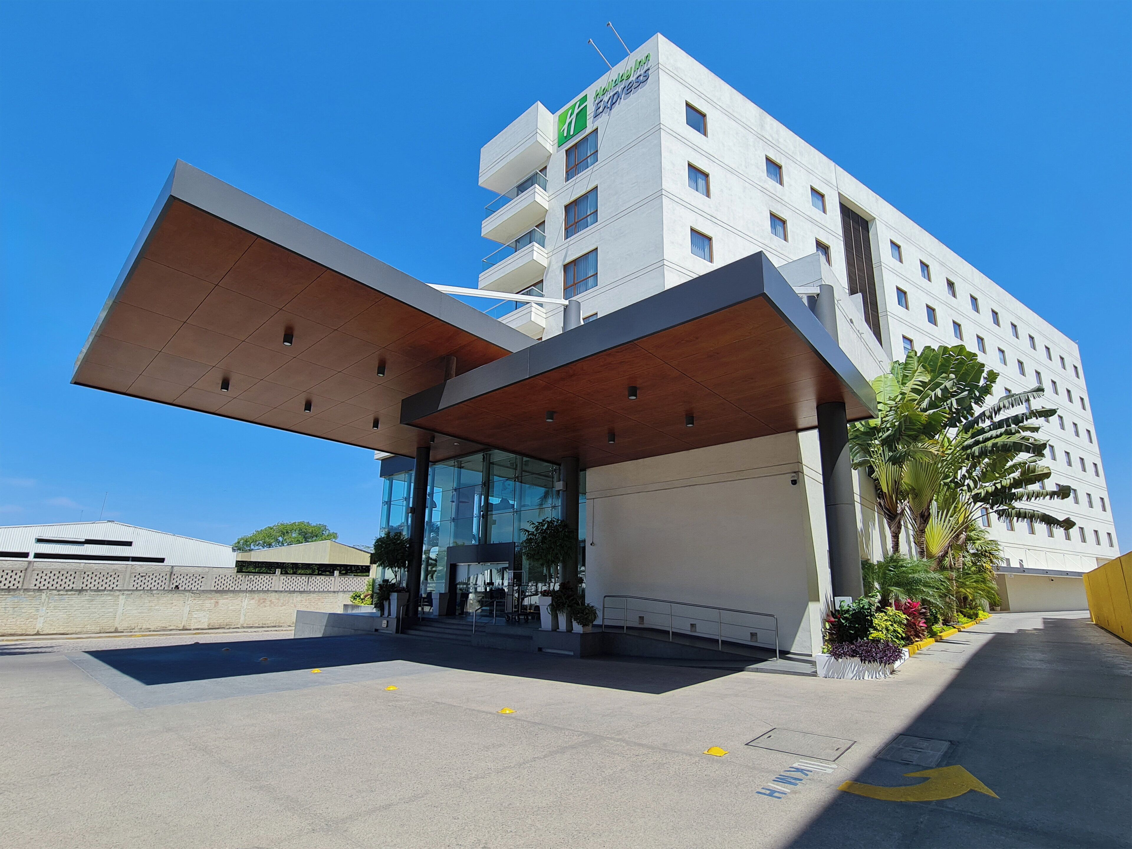 Um hotel moderno com entrada imponente, fachada de vidro e estrutura de telhado plano.