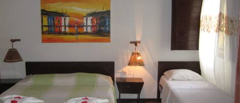 Quarto de hotel com duas camas, um quadro na parede, uma luminária e uma janela com cortinas.