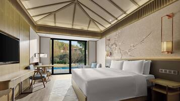 Quarto de hotel moderno com uma cama grande, uma mesa, uma cadeira e uma televisão.