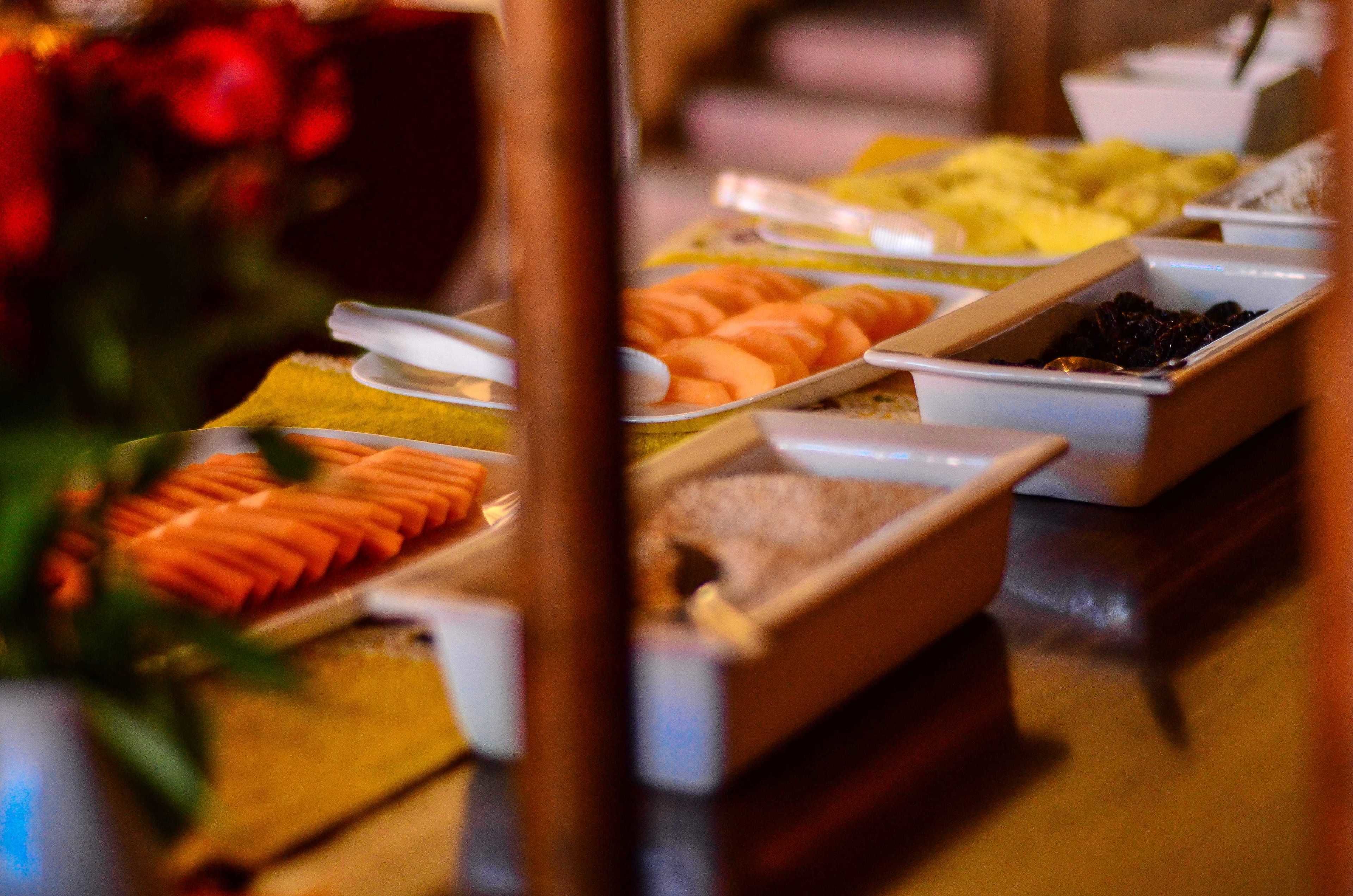Buffet com diversos alimentos, incluindo frutas, legumes e outros pratos.