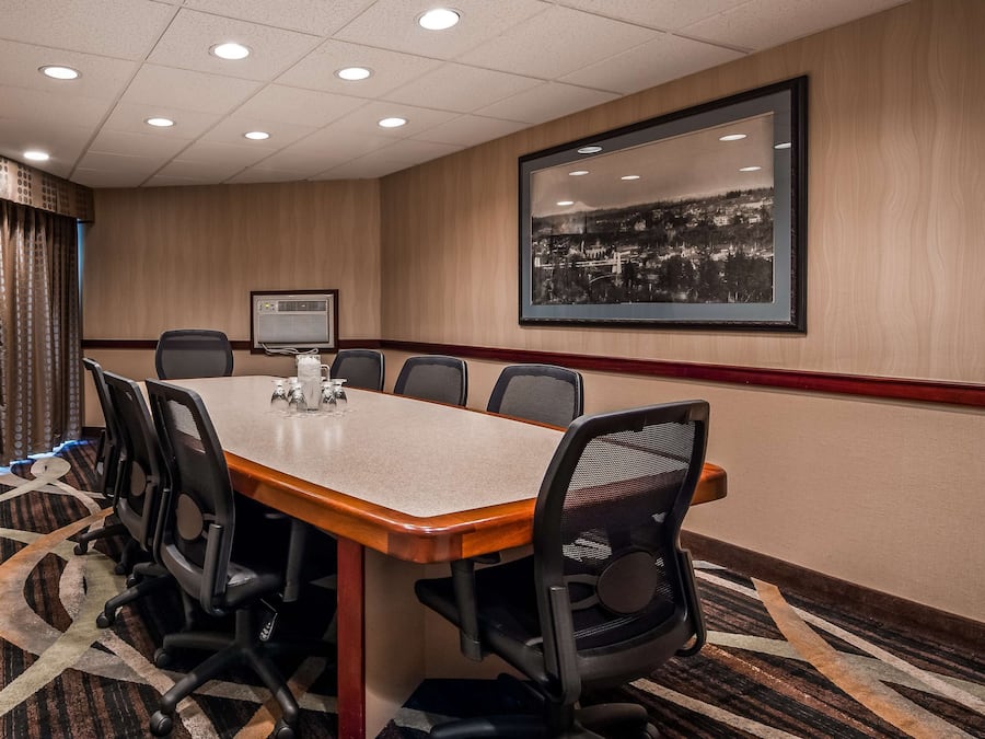 Uma sala de conferências com uma mesa comprida, cadeiras, uma tela de projetor e quadros nas paredes.