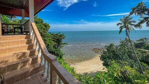 Vista costeira com uma escadaria que leva a um espaço coberto com vista para o mar.