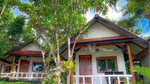 Duas casas de madeira com paredes brancas e telhados vermelhos, rodeadas por vegetação exuberante.