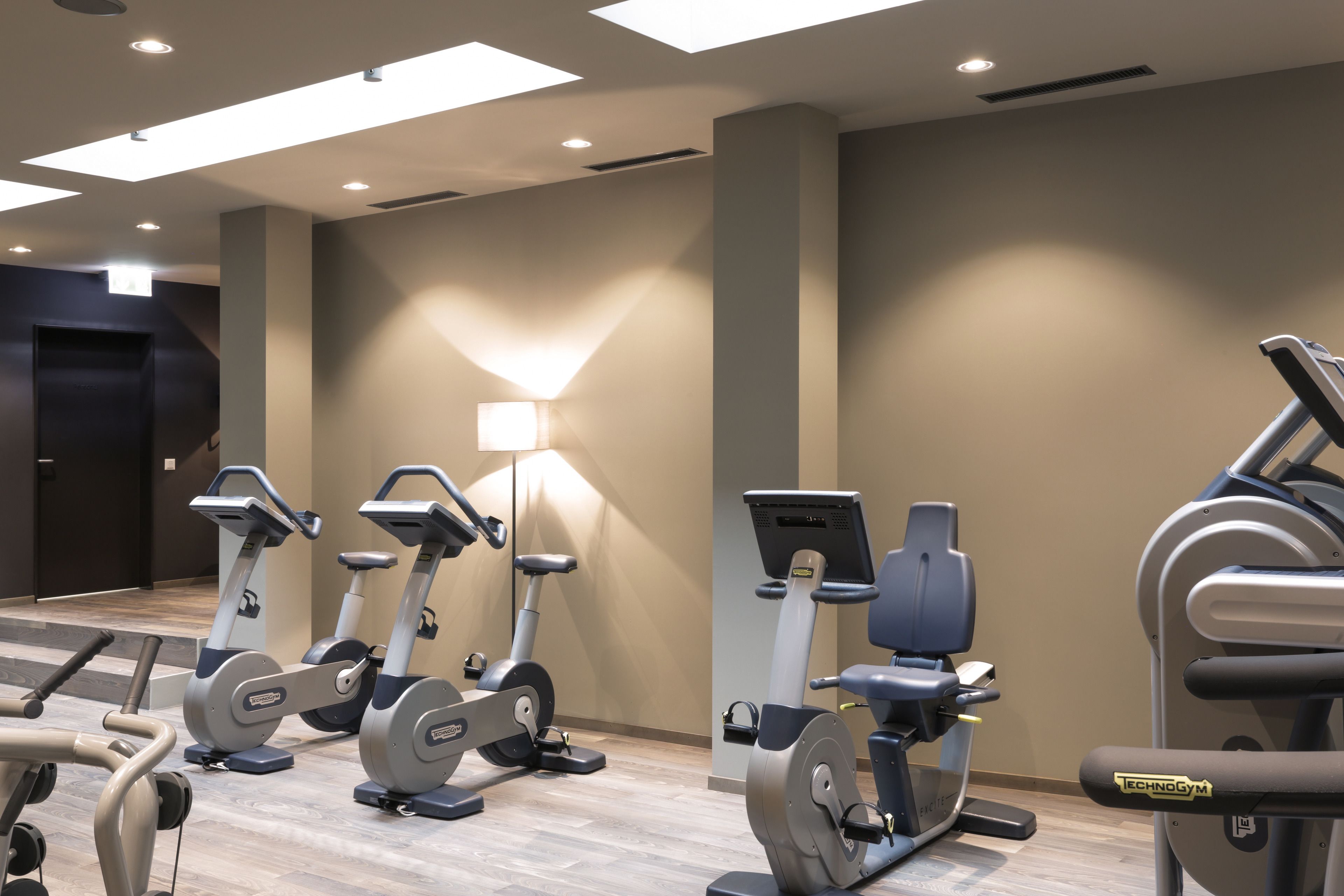 Uma academia com máquinas de cardio, esteira e bicicleta ergométrica.