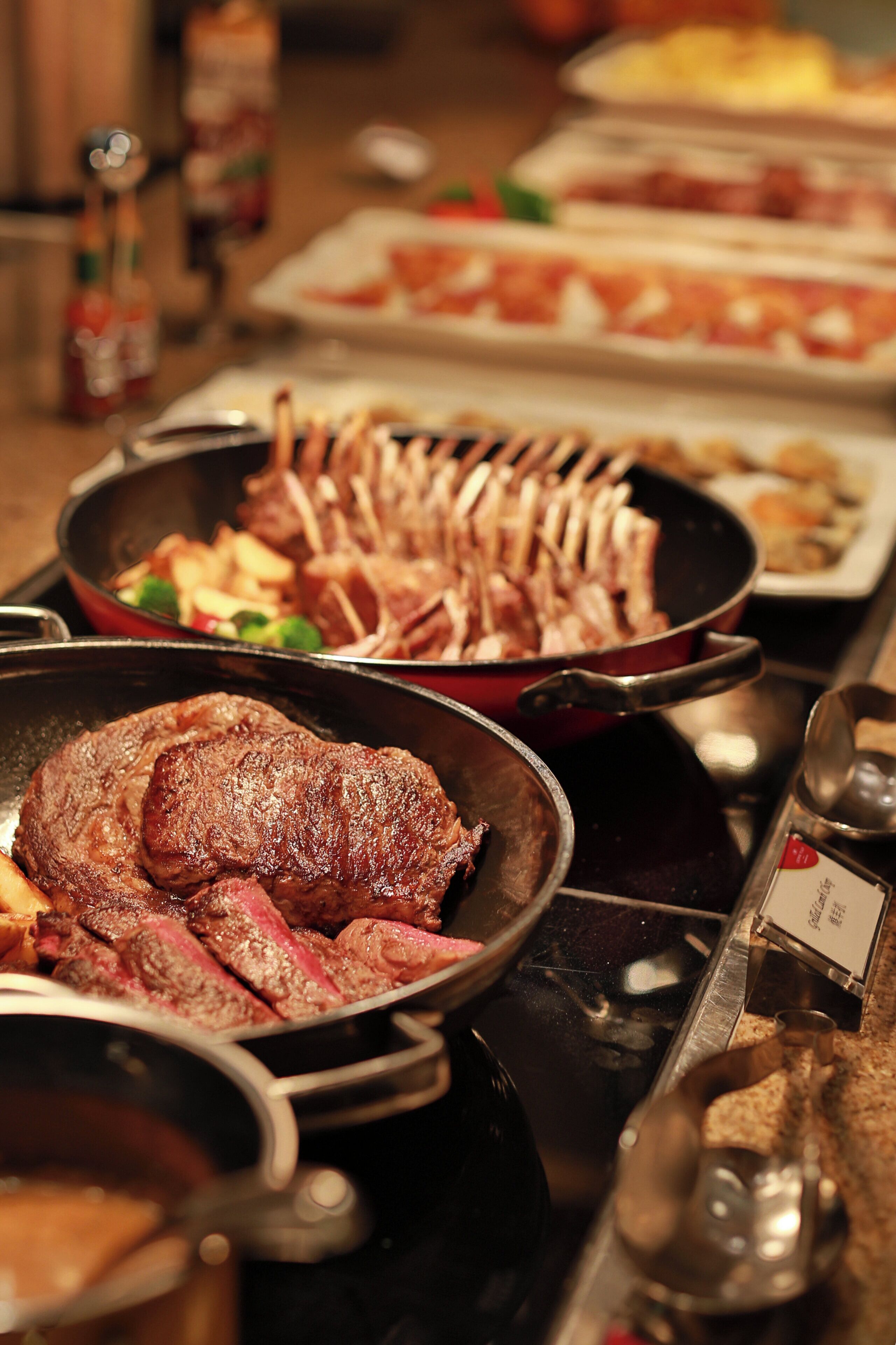 Buffet variado com pratos como bife, legumes e outros alimentos já preparados.
