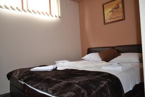 Uma cama bem arrumada com lençóis brancos e um cobertor marrom, um travesseiro marrom e uma toalha branca dobrada ao lado.