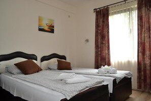 Quarto de hotel com duas camas, um quadro na parede e uma janela com cortinas.