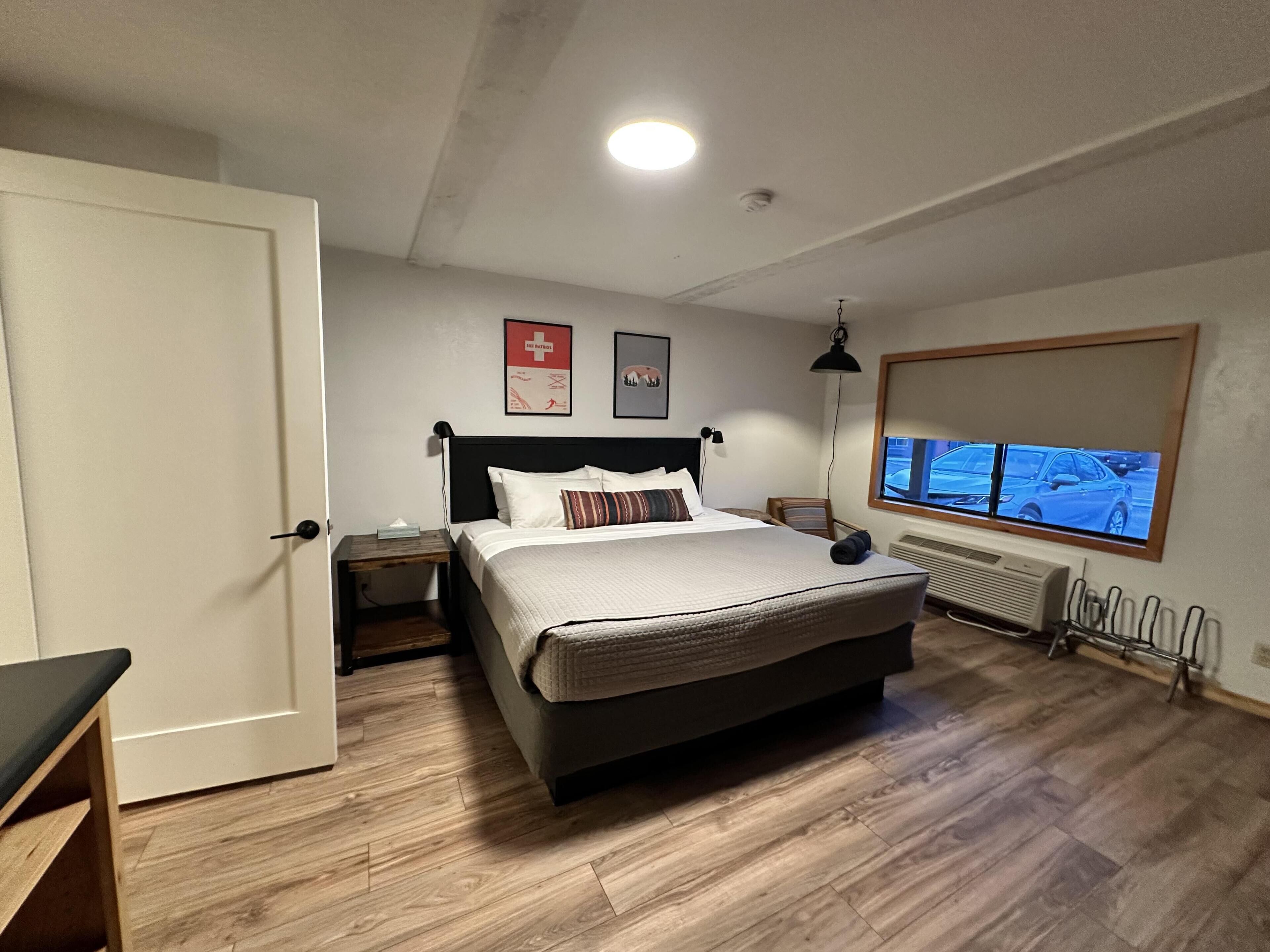 Quarto com cama, mesas de cabeceira, televisão e janela.
