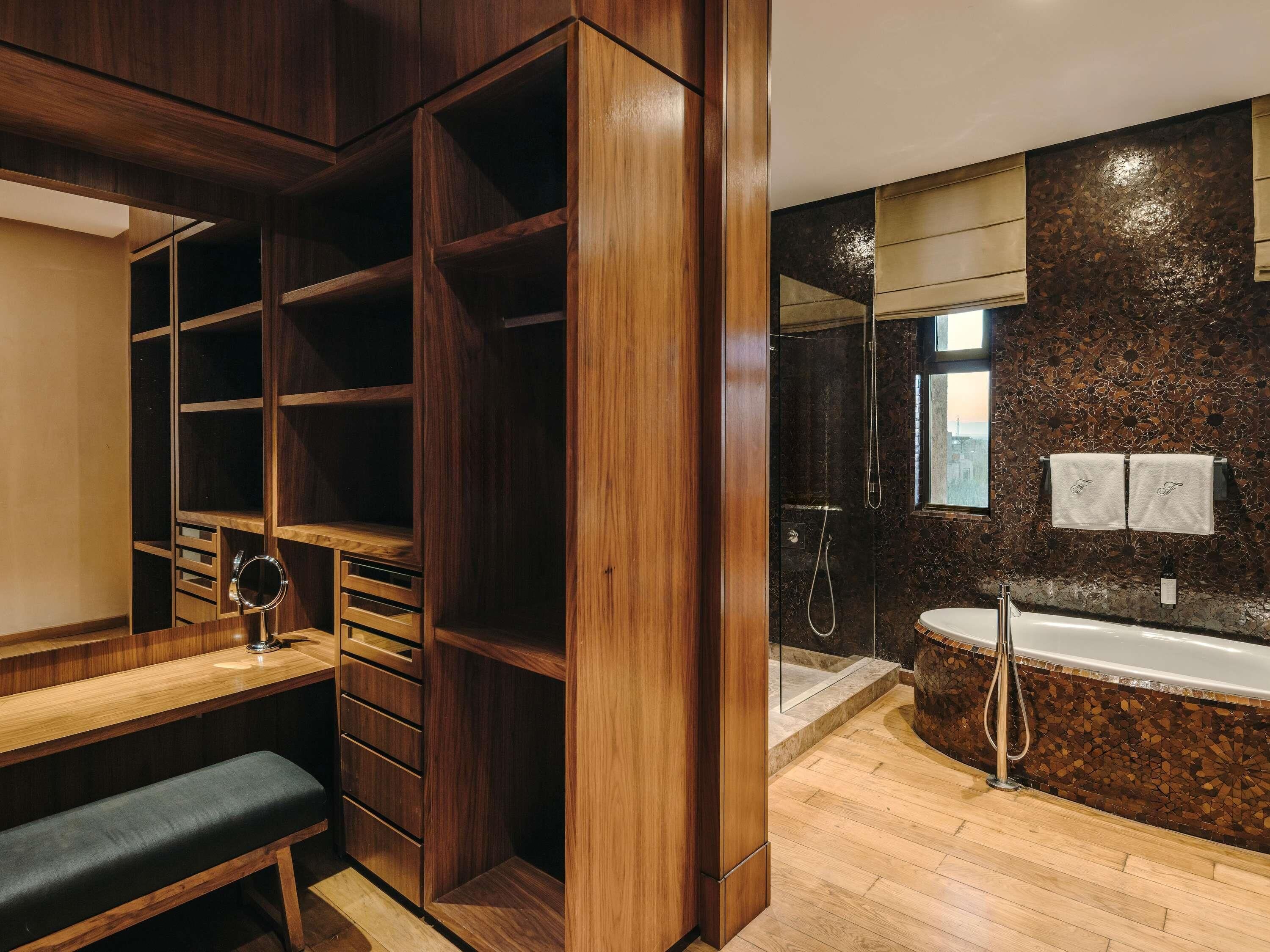 Uma casa de banho moderna com cabine de duche, toucador com espelho e um banco.