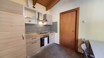 Uma cozinha moderna com armários de madeira clara, fogão embutido e teto de madeira.