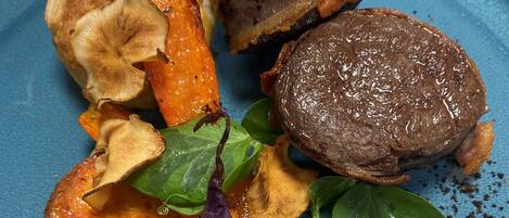 Um prato com bife, batatas assadas e cebola vermelha.