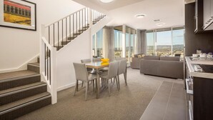 Um apartamento moderno com escada, sala de jantar, sala de estar e grandes janelas com vista para a cidade.