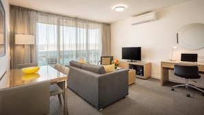 Quarto de hotel moderno com sofá, mesa de jantar, televisão e área de trabalho.