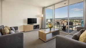 Quarto de hotel moderno com uma grande porta de vidro deslizante que dá para uma varanda com vista para a cidade.