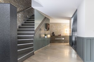 Um interior moderno com escada, uma mesa de apoio de vidro e um detalhe decorativo na parede.