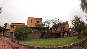Um pátio com um caminho de pedra que leva a um edifício com telhado plano e várias janelas.
