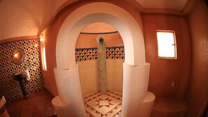 Casa de banho com chão em azulejo, um pilar de pedra e uma janela.