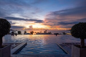 Piscina infinita com vista para o pôr do sol sobre o mar.