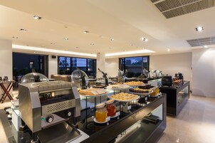 Buffet montado com churrasqueira de serviço livre, diversos alimentos e acompanhamentos.