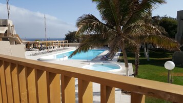 Uma área de piscina com espreguiçadeiras e uma palmeira.