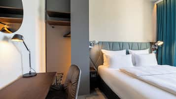 Quarto de hotel com cama, abajures, escrivaninha e cadeira.