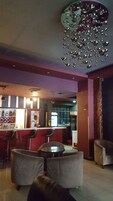 Uma área de bar com banquetas, um balcão com garrafas e um detalhe decorativo no teto.