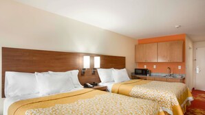 Quarto de hotel com duas camas, cabeceira de madeira, micro-ondas, pia e armário.