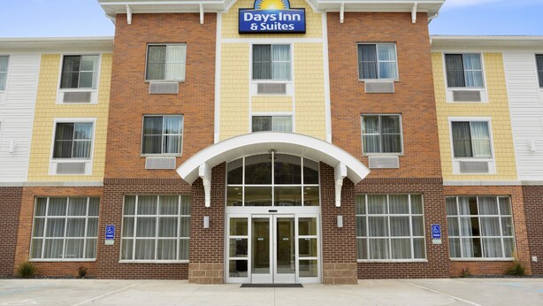 Edifício Days Inn & Suites com fachada de tijolos, janelas amplas e entrada destacada com porta de vidro.