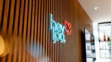 Um letreiro de neon com o texto 'hey you' em uma parede de madeira.