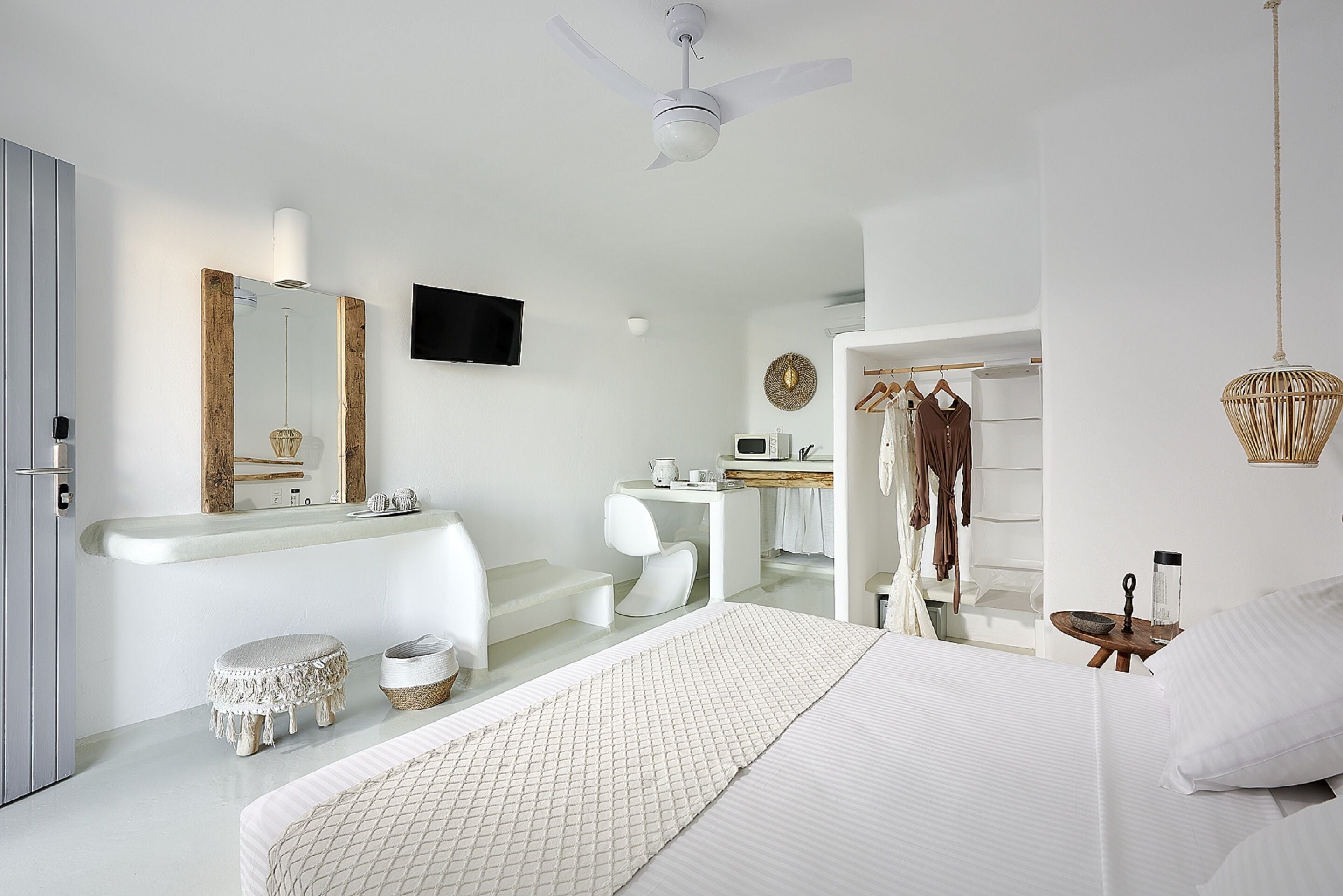 Quarto moderno com uma cama grande, uma penteadeira com espelho, uma escrivaninha e um closet espaçoso.