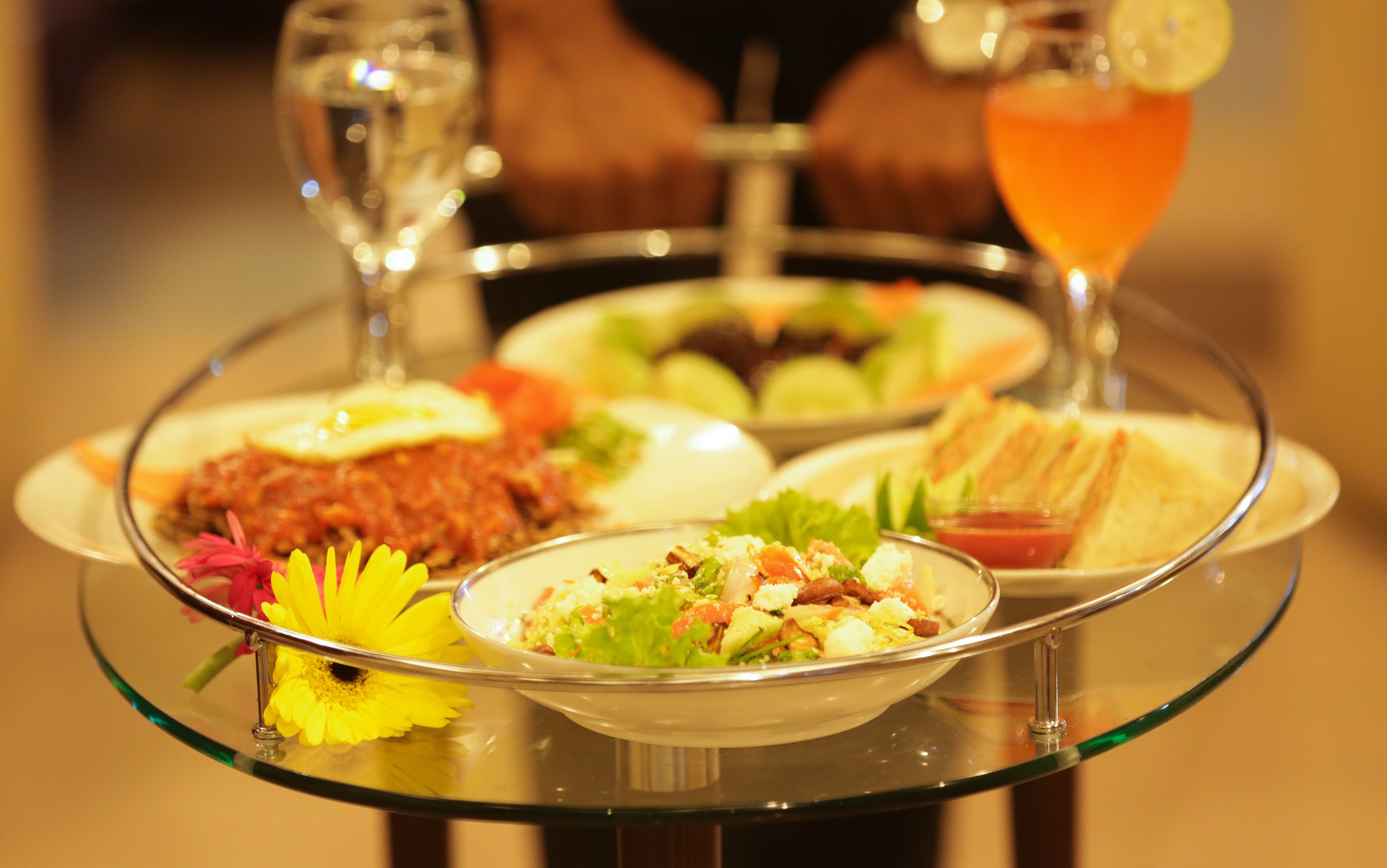Mesa de vidro com diversos pratos e bebidas.
