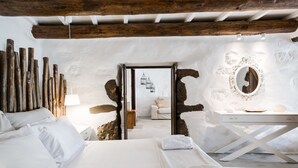 Quarto com cama grande, mesa de cabeceira, cômoda e espelho na parede.