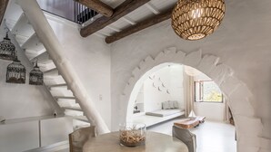 Um interior moderno com escada, uma mesa de madeira redonda com cadeiras e um lustre.