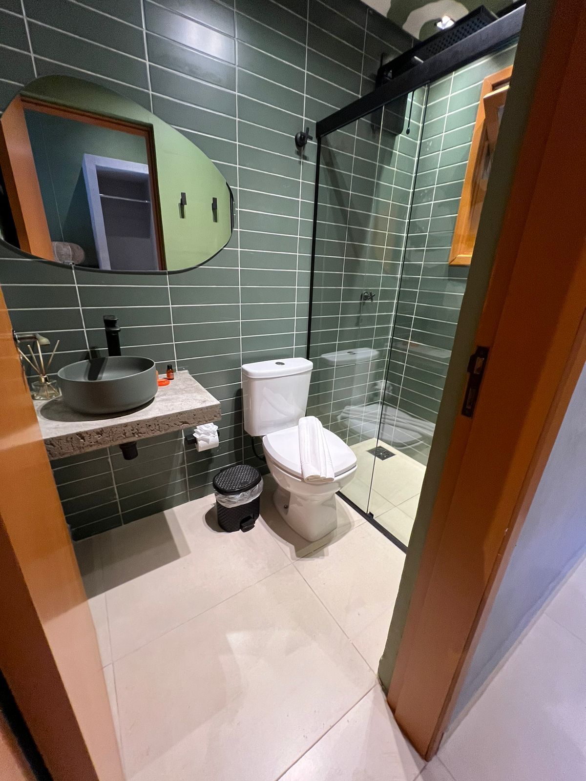 Casa de banho com sanita, lavatório e zona de duche separada por vidro.