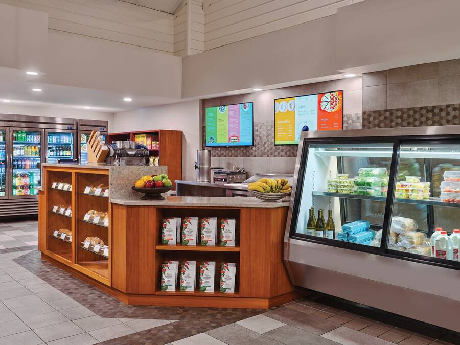 Um balcão de pastelaria com pão e doces, uma vitrine refrigerada com produtos lácteos e um refrigerador de bebidas.