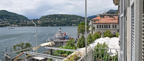 Terraço com área de estar ao ar livre com vista para um lago, um barco na água e edifícios ao fundo.