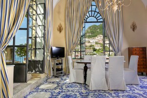 Quarto com uma janela grande, televisão, mesa de jantar com cadeiras e um armário de madeira.