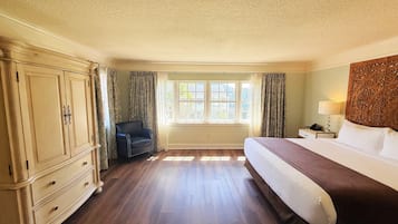 Quarto de hotel com uma cama grande, um guarda-roupa, uma cadeira e uma janela com cortinas.