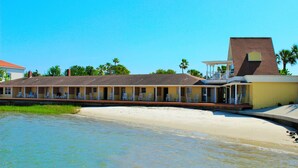 Um motel à beira-mar com vários quartos, piscina e vista para a praia.